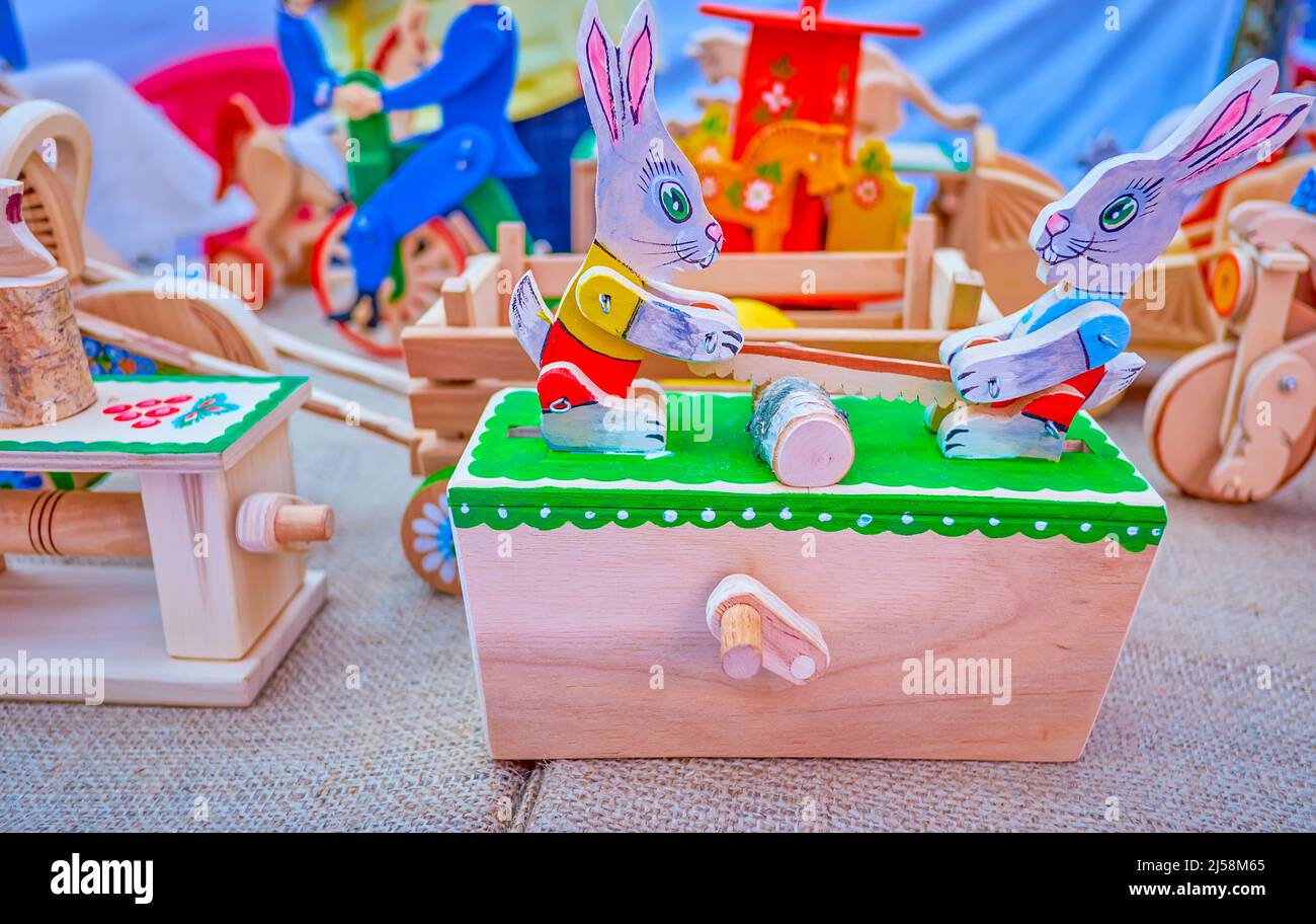 The wooden moving painted toy in form of rabbits sawing firewood on ...
