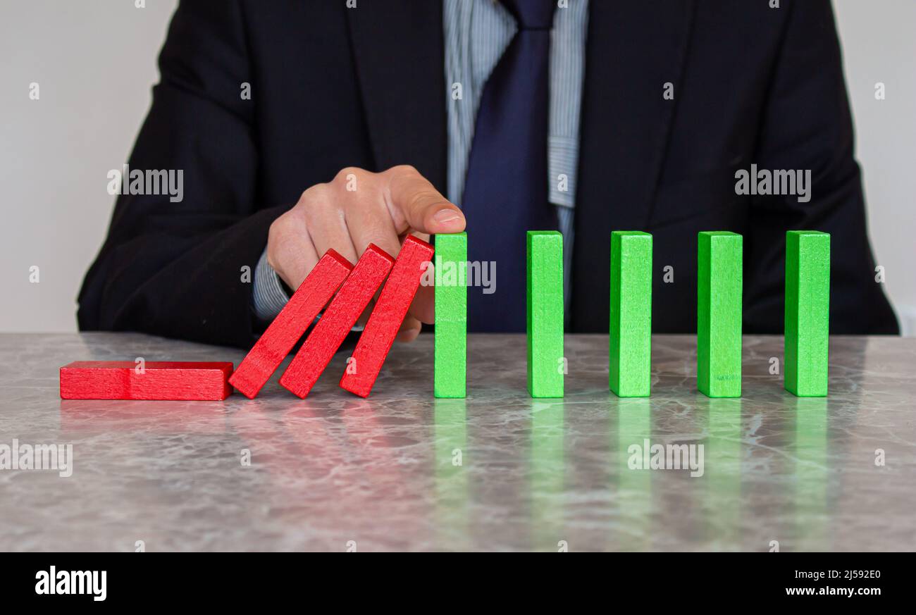 Businessman is stopping the falling wooden blocks. Crisis management ...