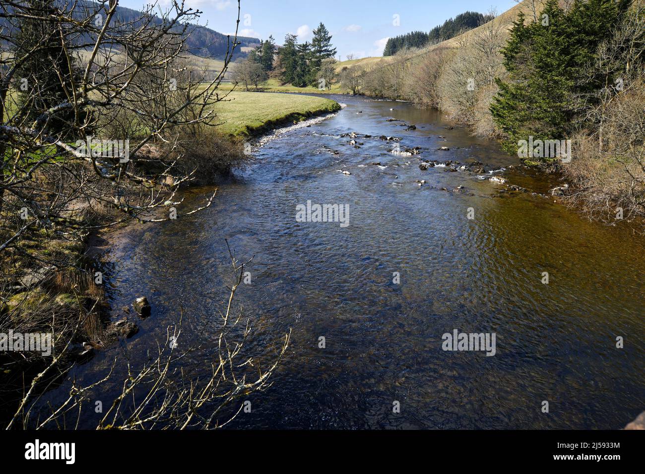 A sunny view upstream of the River Esk from the bridge at Bentpath ...