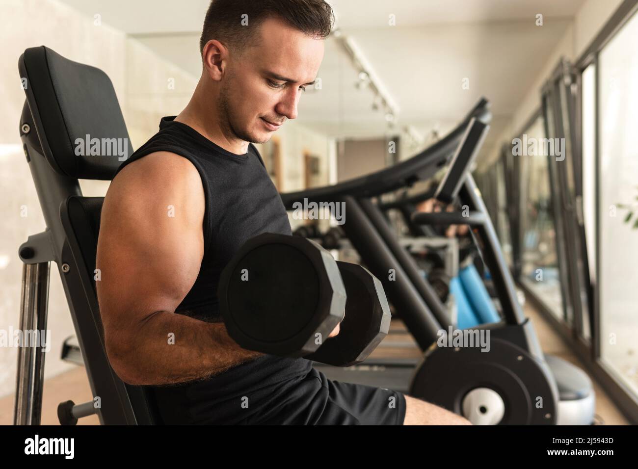 Athletic man working out with a dumbbells during his workout in the gym ...