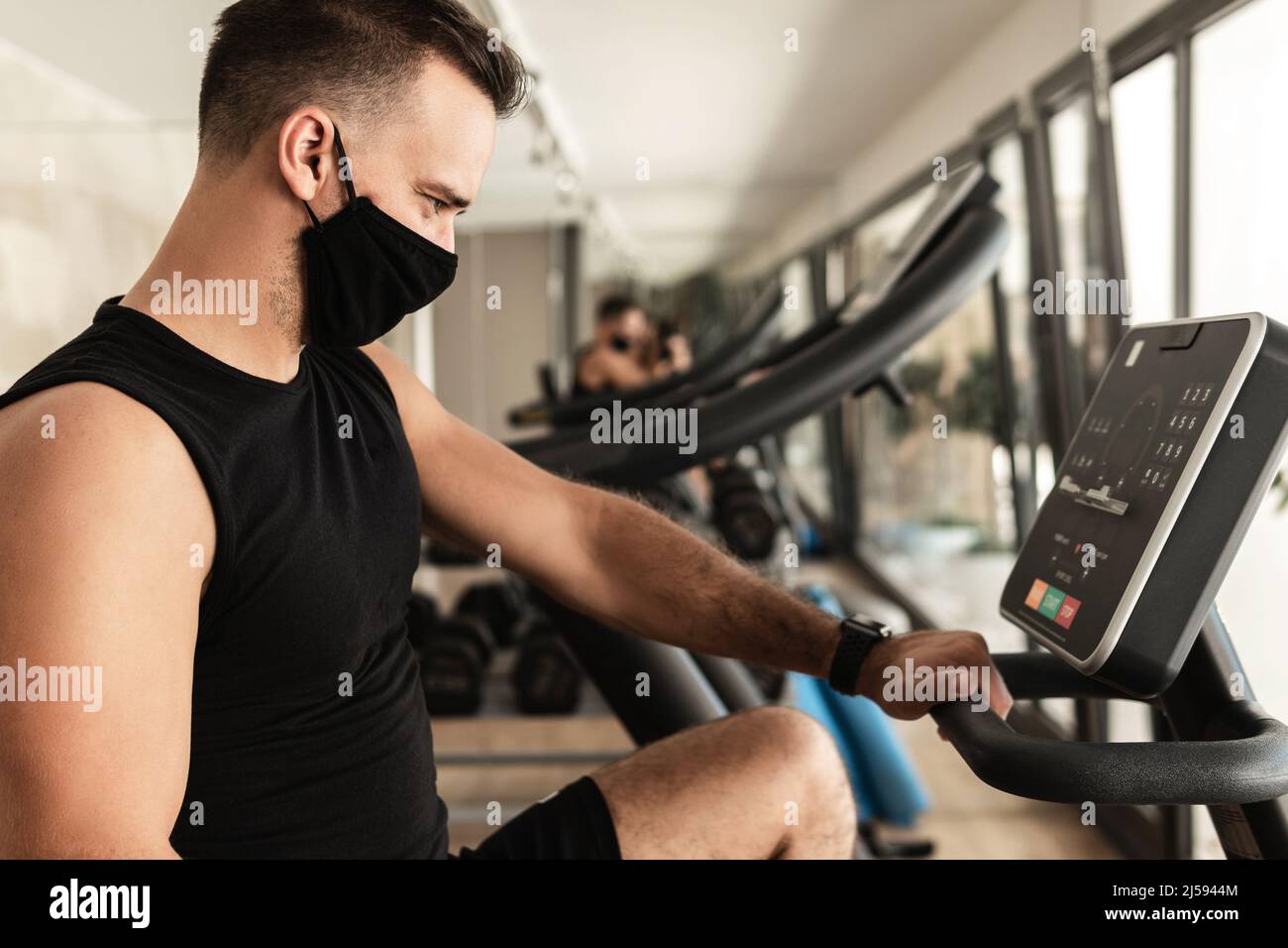 Young athletic man wearing a prevention face mask during his workout in ...