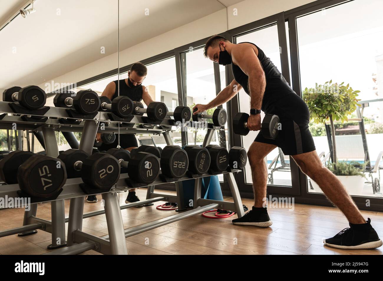 New normal concept. Young athletic man wearing a prevention face mask ...