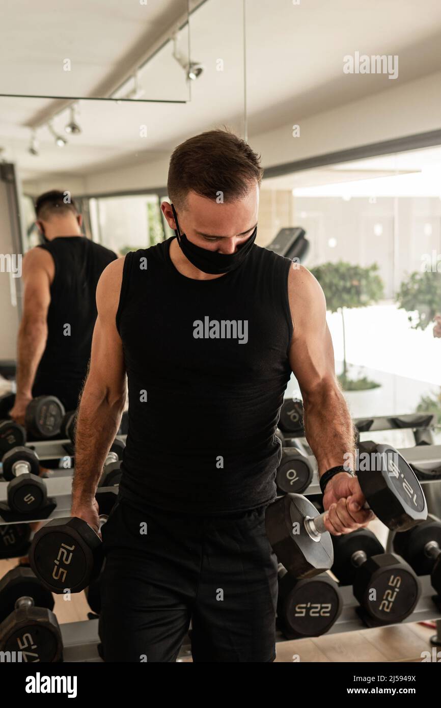 New normal concept. Young athletic man wearing a prevention face mask ...