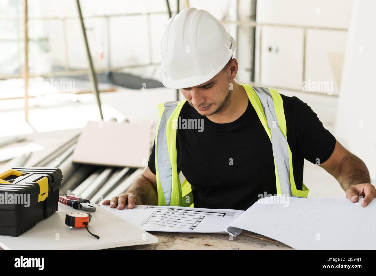 Young is worker checking blueprints during his work on a construction ...
