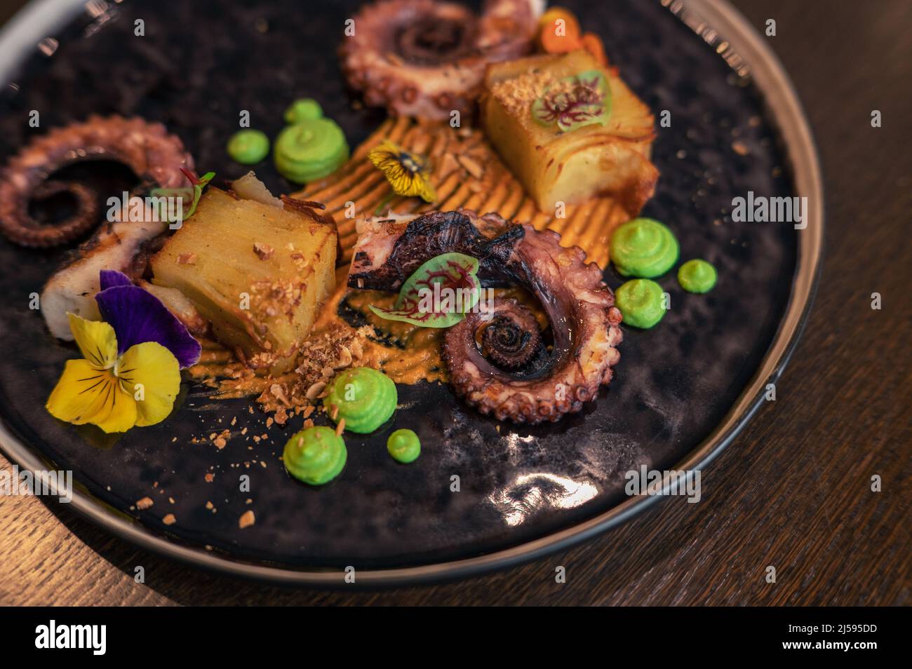 Octopus with potatoes on pea mash decorated with edible flowers Stock ...