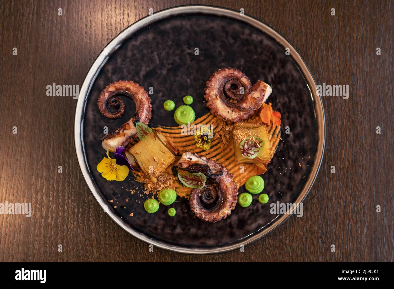 Octopus with potatoes on pea mash decorated with edible flowers Stock ...