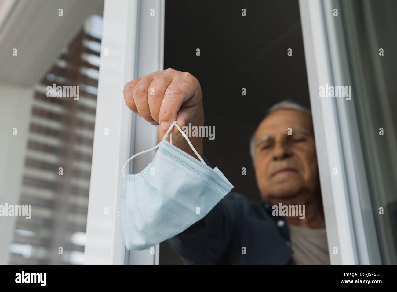 Elderly man is throwing away used prevention mask. Symbol of pandemic ...