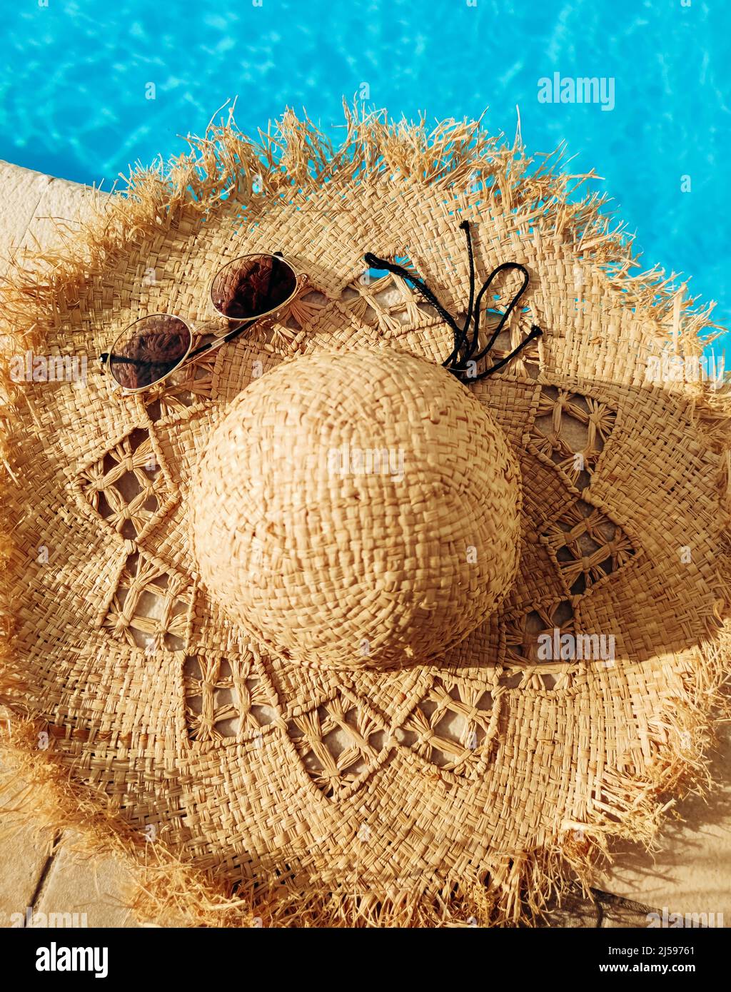Sunglasses and straw hat on marble swimming pool side with clear blue ...