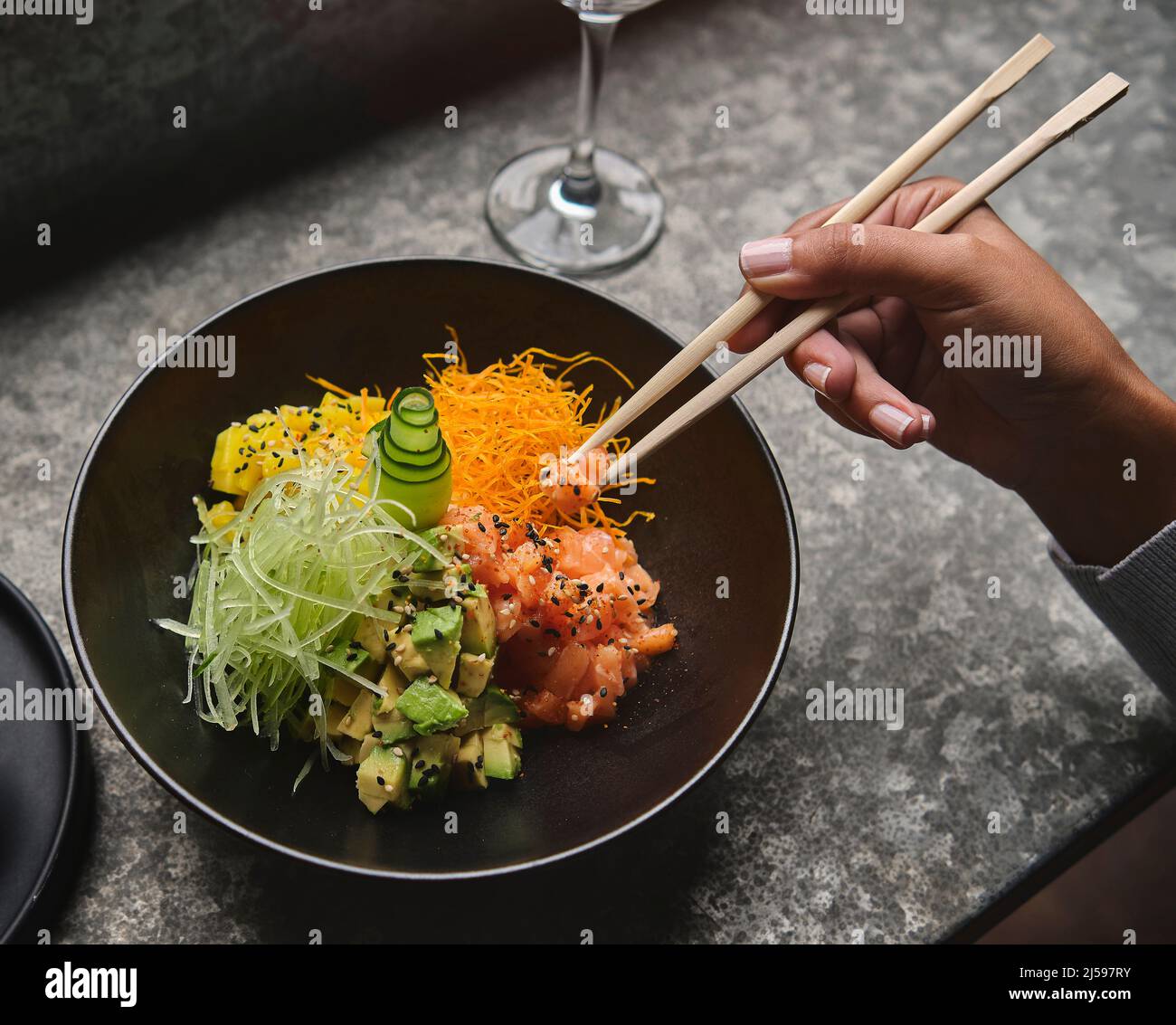 Woman eating traditional Hawaiian dish poke bowl with fork. Diet and ...