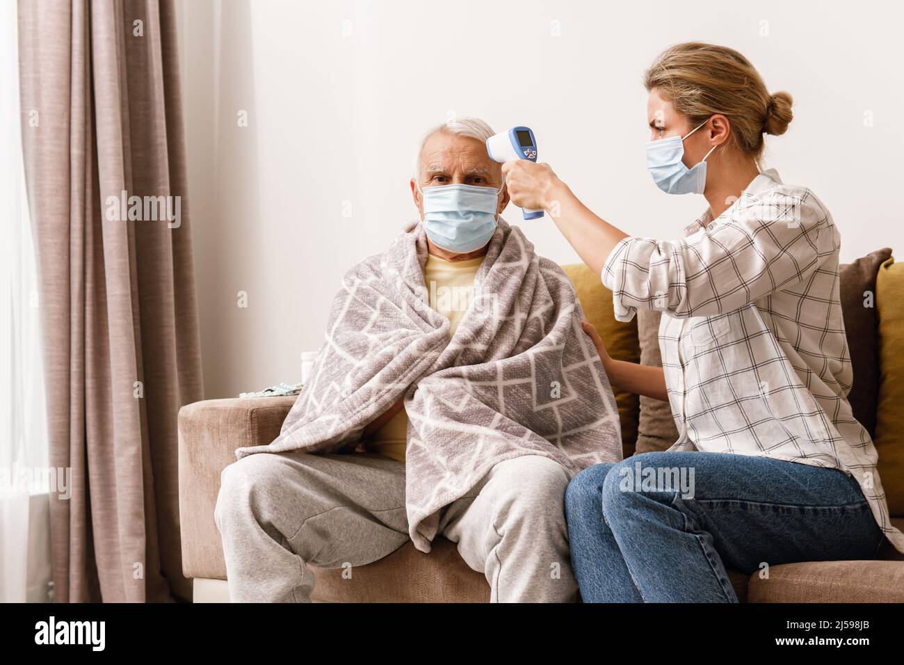 Young woman taking care of her elderly grandfather with a cold syptoms ...