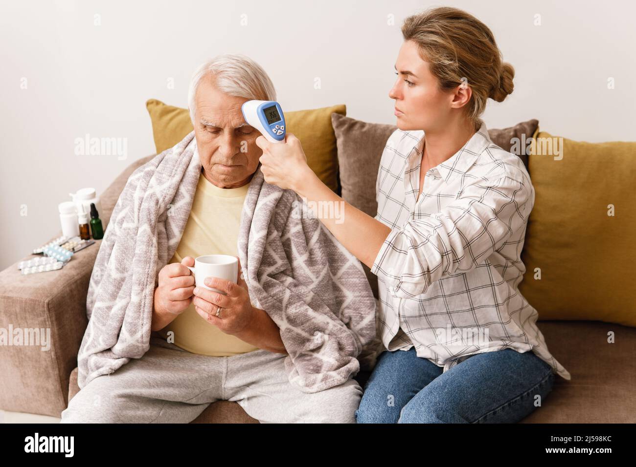 Young woman taking care of her elderly grandfather with a cold syptoms ...