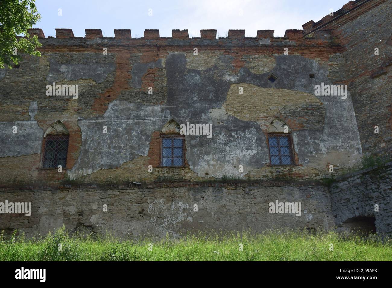 Medieval stone fortress wall with battlements, barred windows and ...