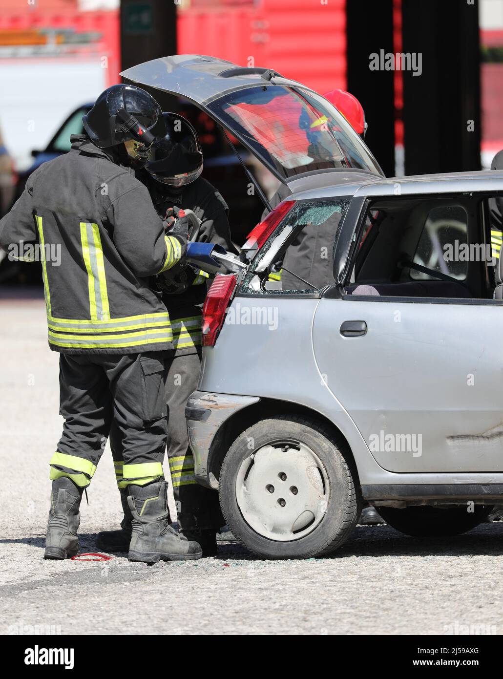 firefighters in action as they shear the sheet metal of a crashed car ...