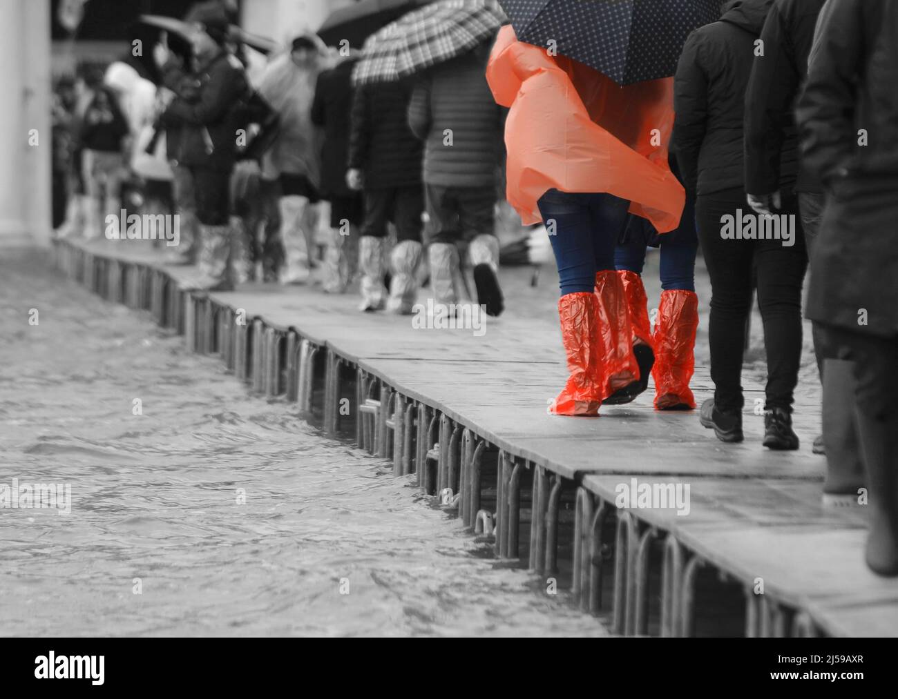 venice at high tide and people walking over the walkway and red spats ...
