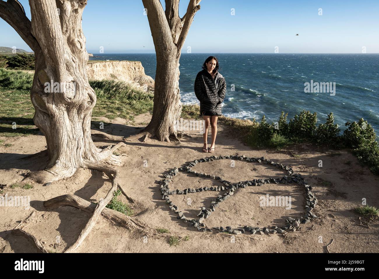 Young Woman Beside Peace Symbol Overlooking the Ocean | Lifestyle Local ...