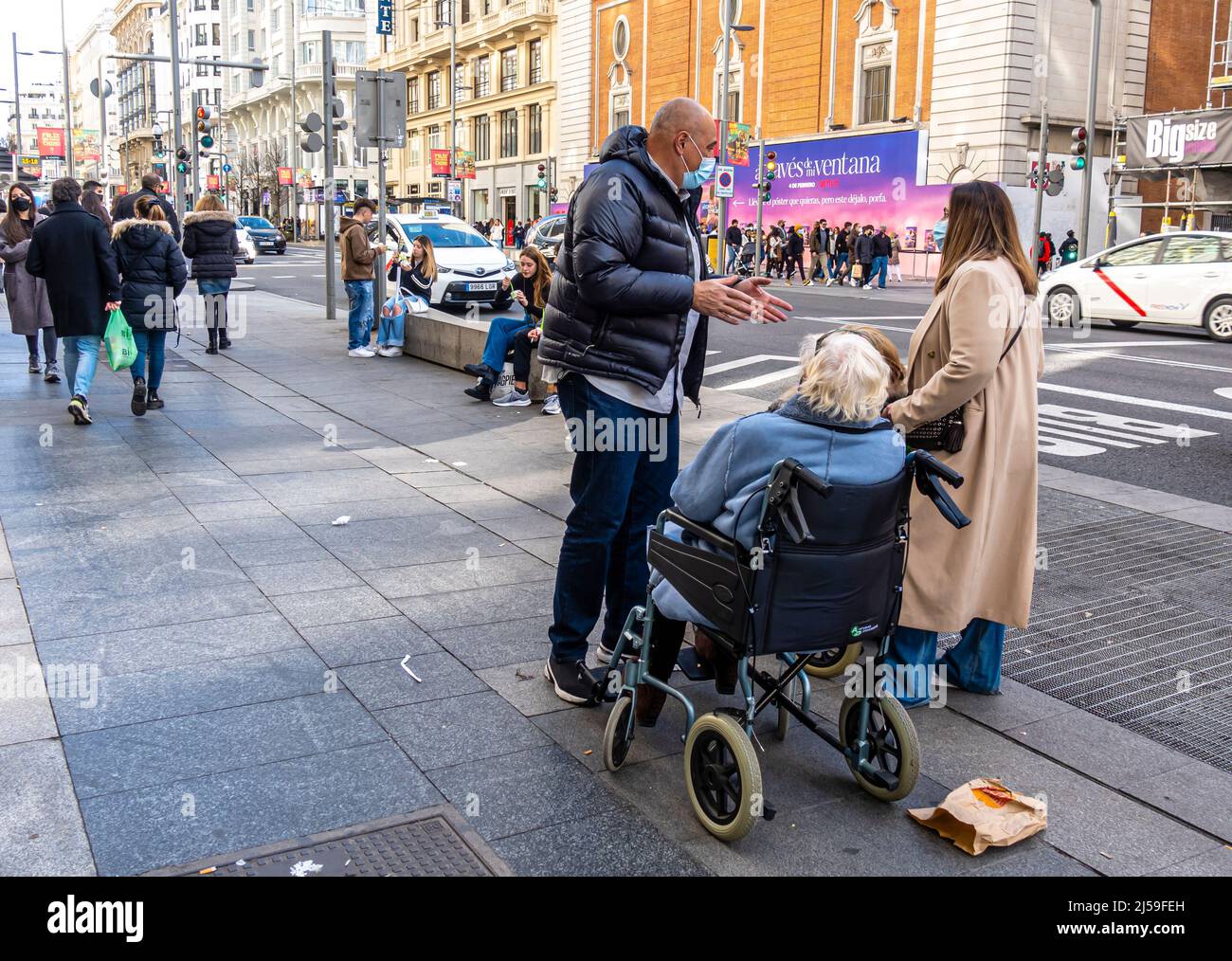 Man and woman caring for an old lady in a wheel chair in the street of ...