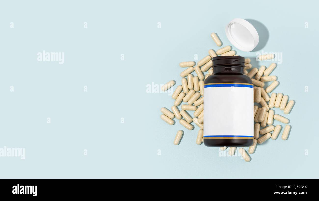 Natural color capsules and glass bottle on a light blue background ...