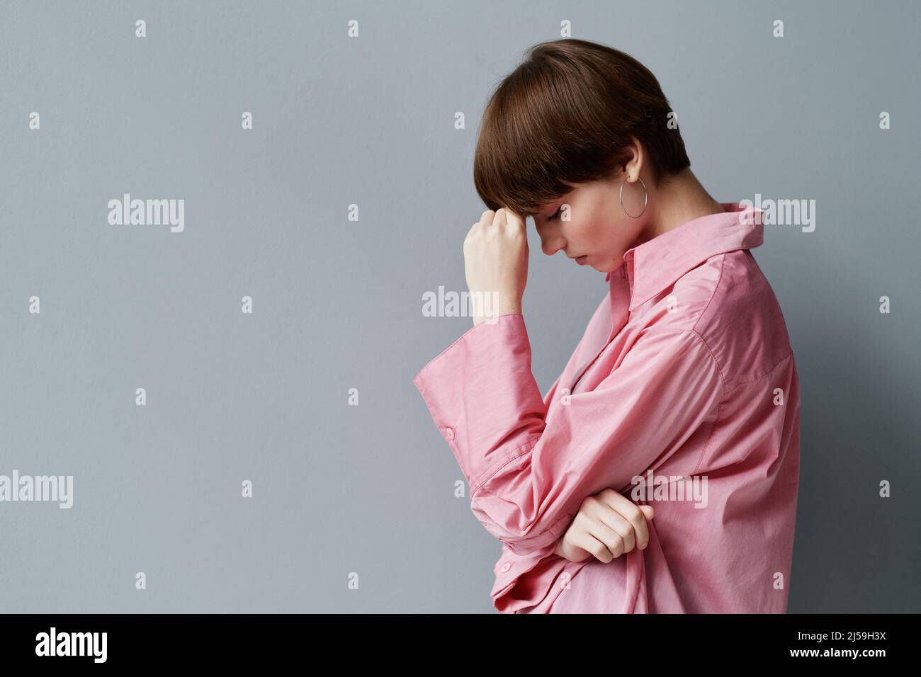 Side view of depressed young Caucasian woman with sort hair touching ...