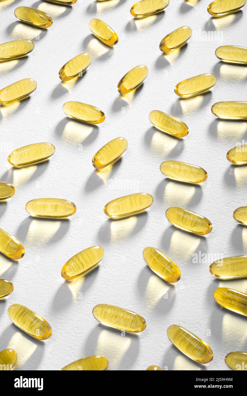 Sunlight passes through Omega-3 capsules lying on a white background ...