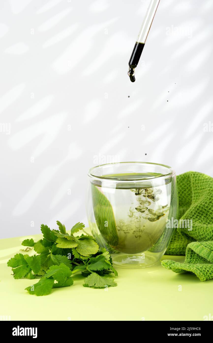Mixing water and liquid chlorophyll with dropper. Fresh herbs and green ...