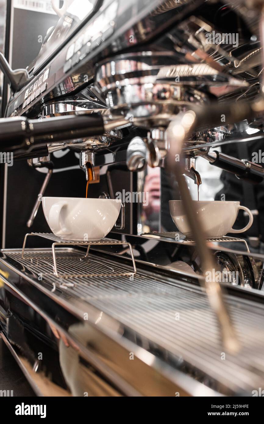 Pouring coffee stream from professional machine in cup. Barista making ...
