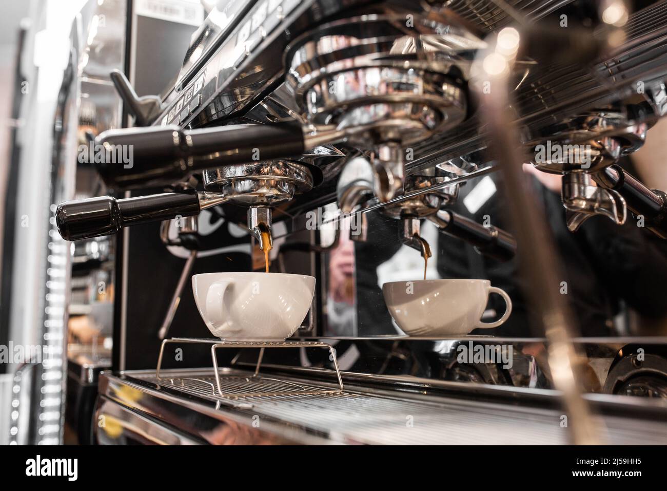 Pouring coffee stream from professional machine in cup. Barista making ...