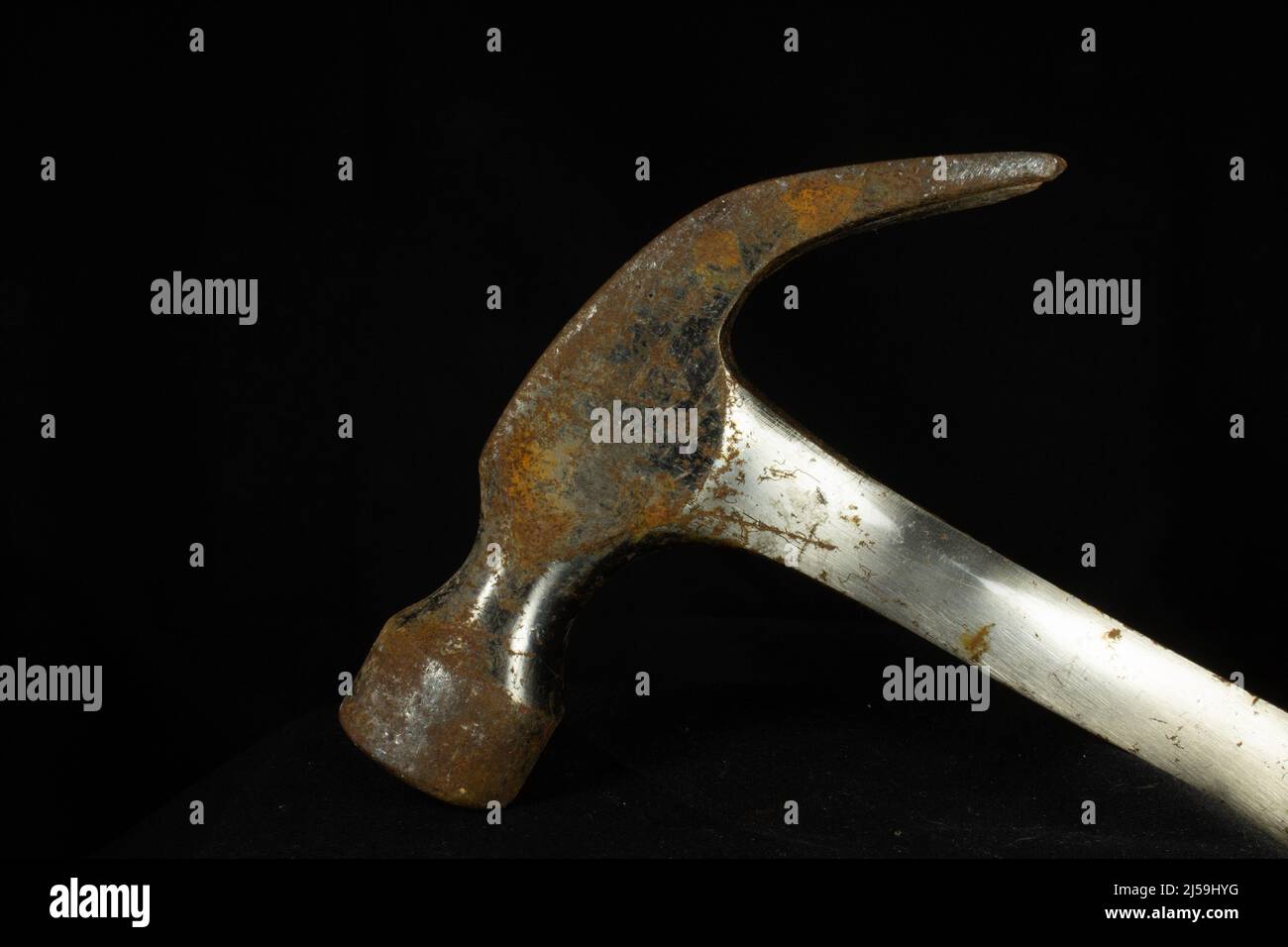 rusty hammer head and shaft with head down isolated on a black ...
