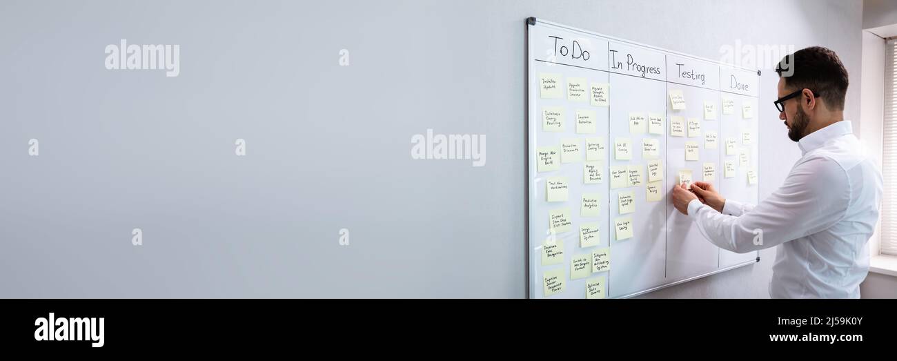 Side View Of Businessman Writing On Sticky Notes Attached To White ...
