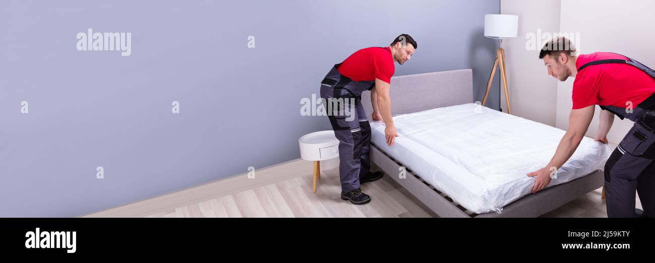 Two Male Professional Movers In Uniform Placing The Mattress Over The ...