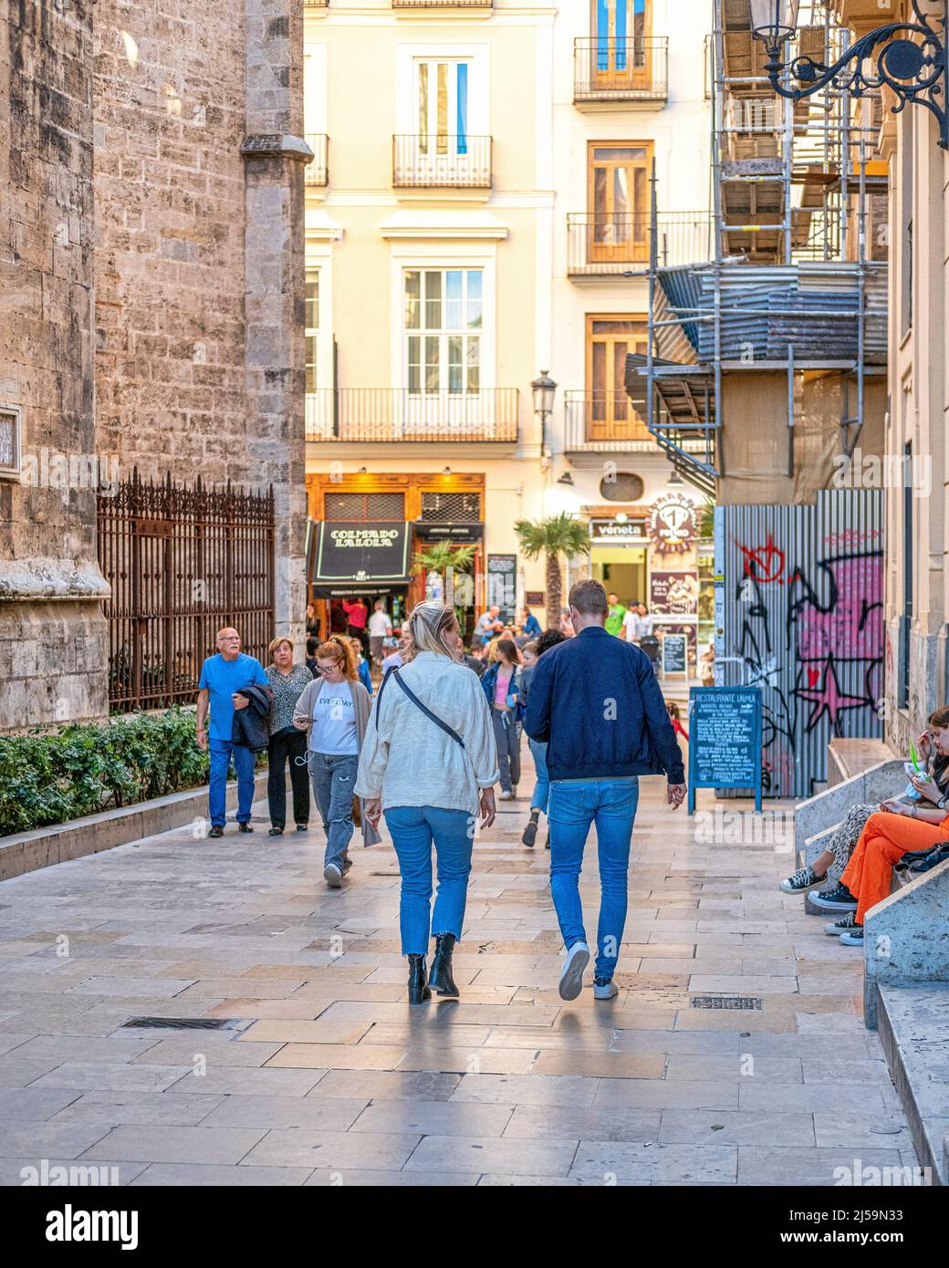 Tourists walking on a narrow street with colonial style buildings on ...