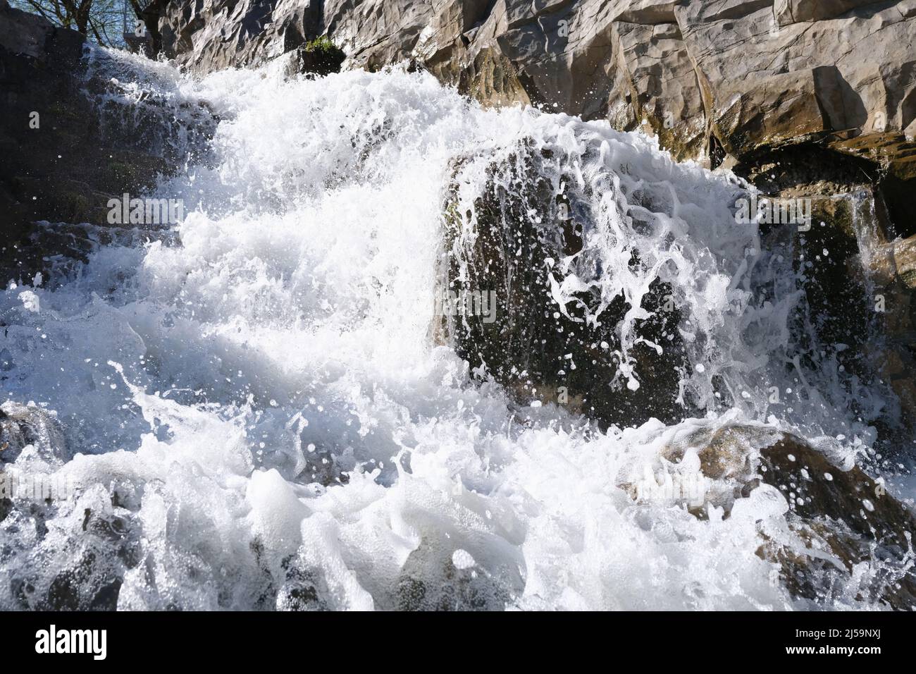 Rapid waterfall with foaming water in rocks background Stock Photo - Alamy