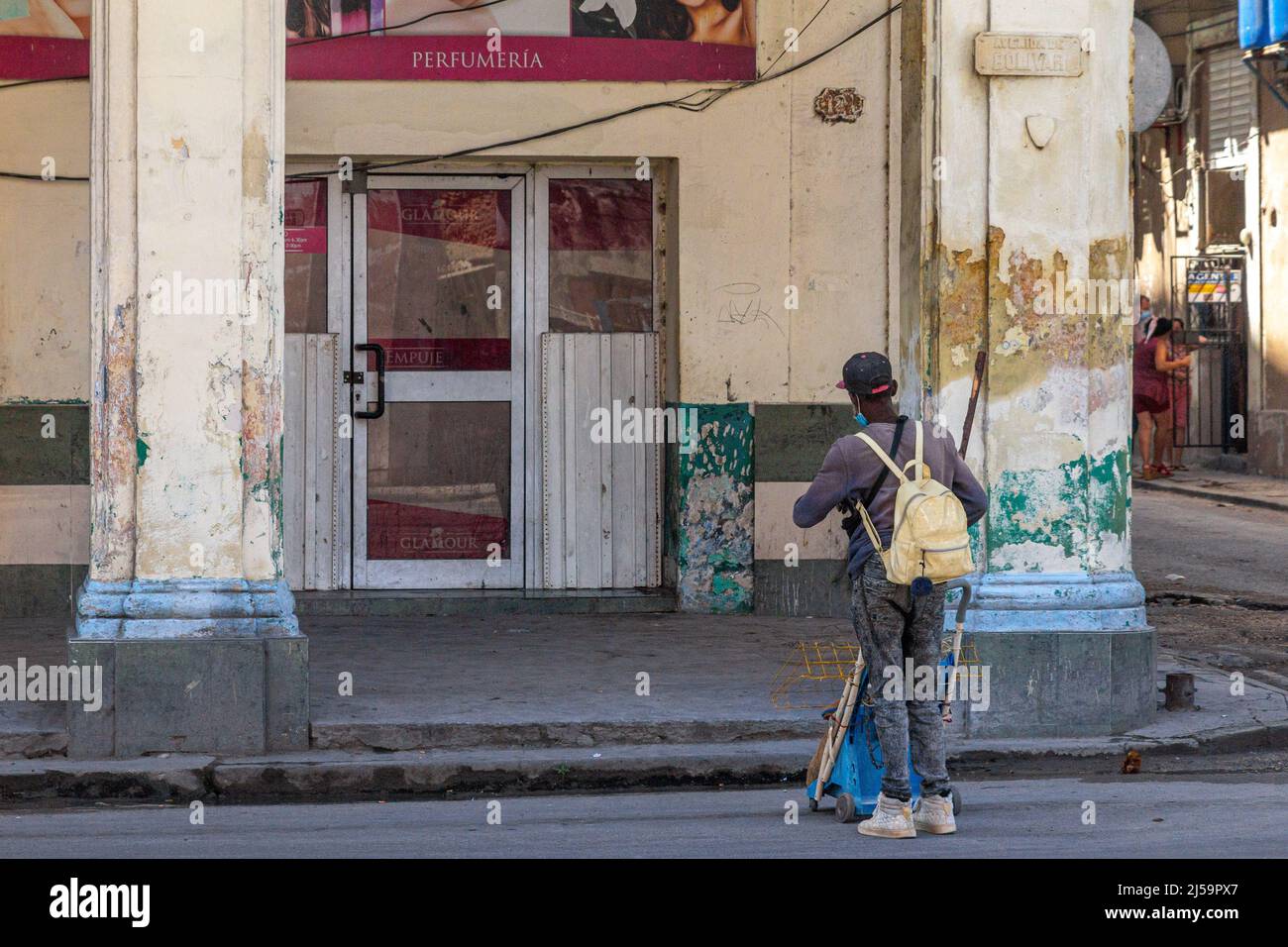 An Afro-Caribbean Cuban man is seen in a city corner with a rustic cart ...