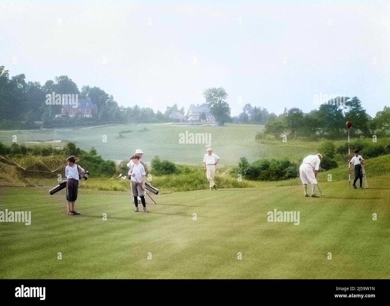 1920s MEN THREE GOLFERS AND BOYS THREE CADDIES PUTTING ON 16TH GREEN ...