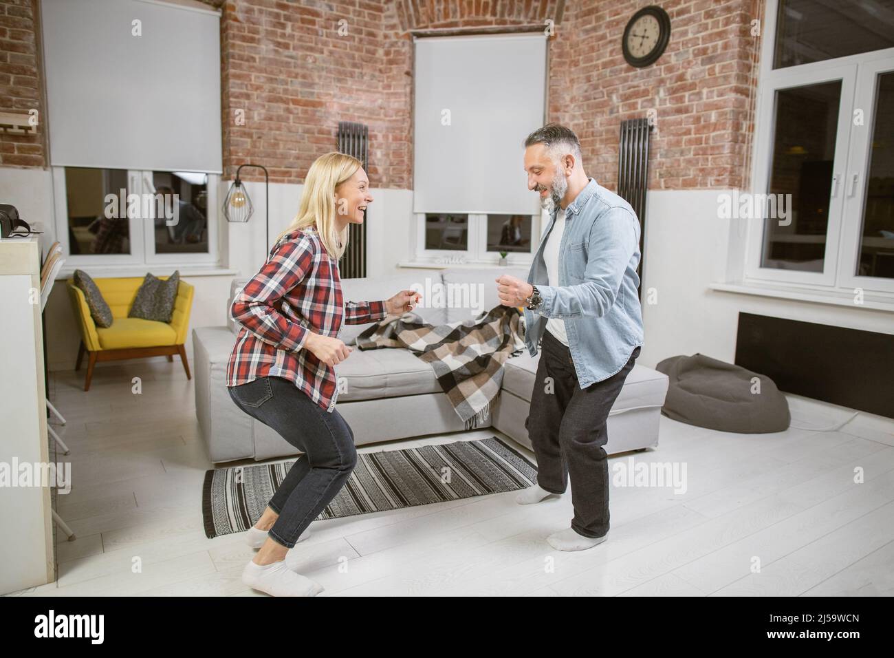 Joyful mature couple moving actively at home while spending free time ...