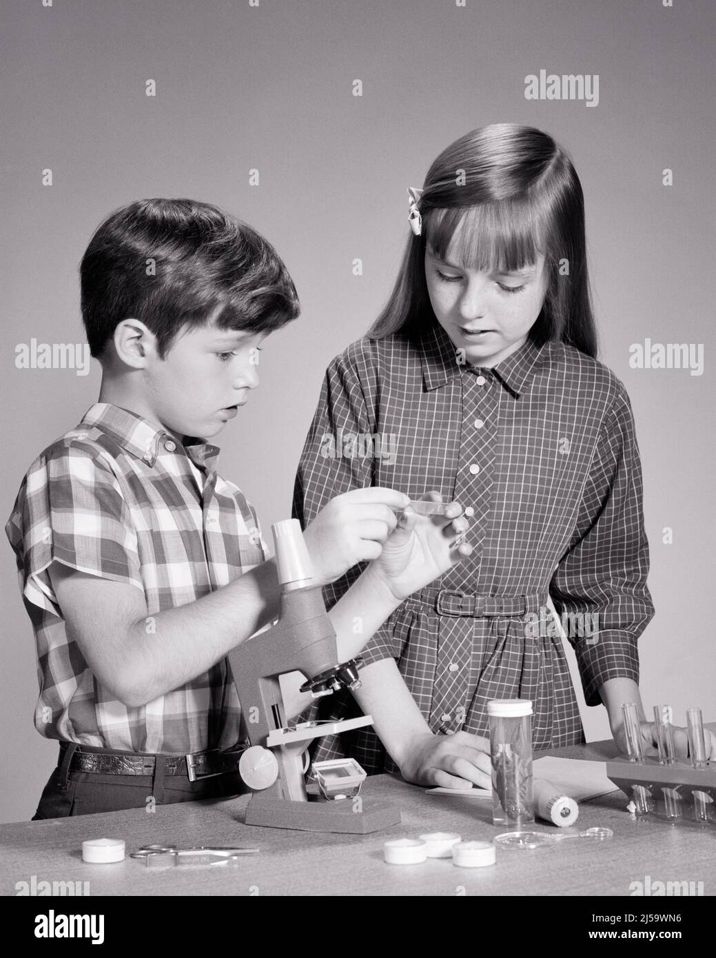 1960s BOY AND GIRL WORKING WITH A HOME CHEMISTRY SET WITH A MICROSCOPE ...