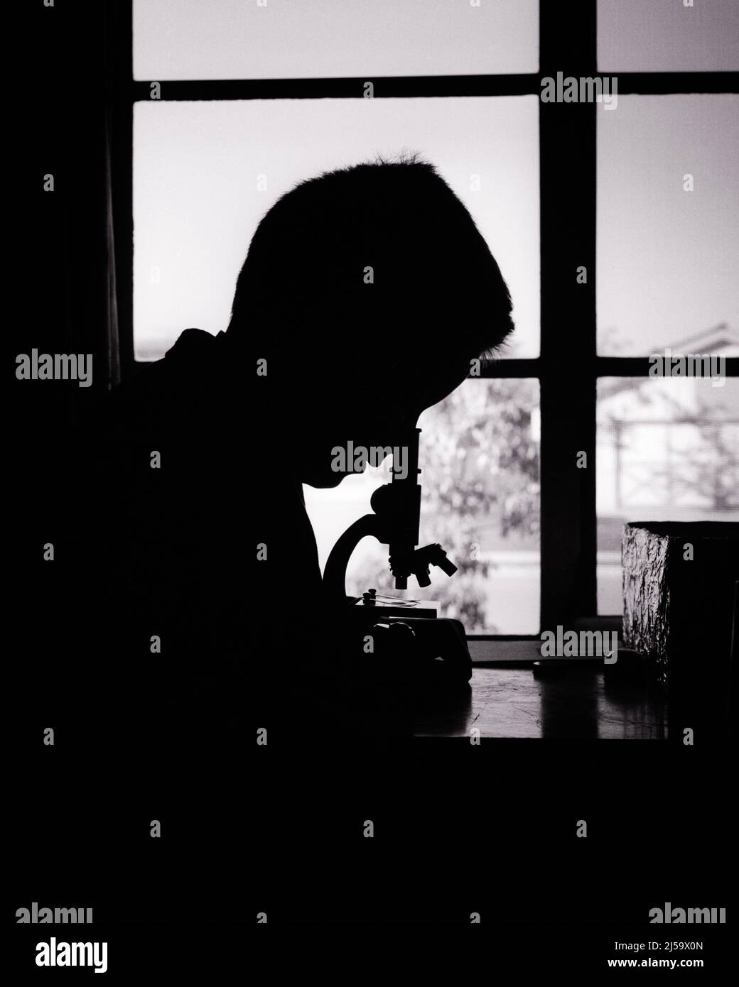 1970s ANONYMOUS SILHOUETTE BOY LOOKING THROUGH MICROSCOPE AT HOME ...