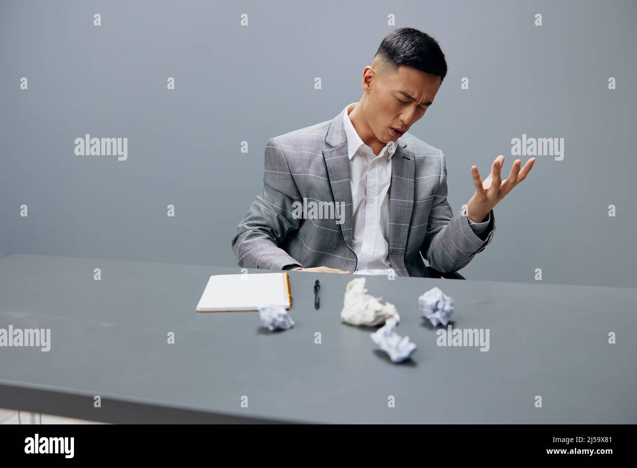worker in a suit sits at a table emotions crumpled paper isolated ...