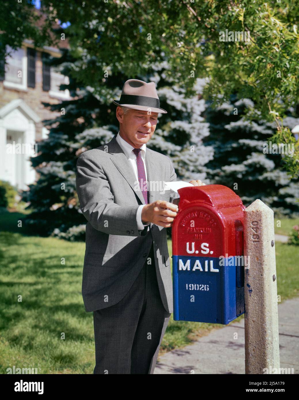 1960s BUSINESSMAN PUTTING MAIL INTO AN OLD FASHION CAST IRON US MAIL ...