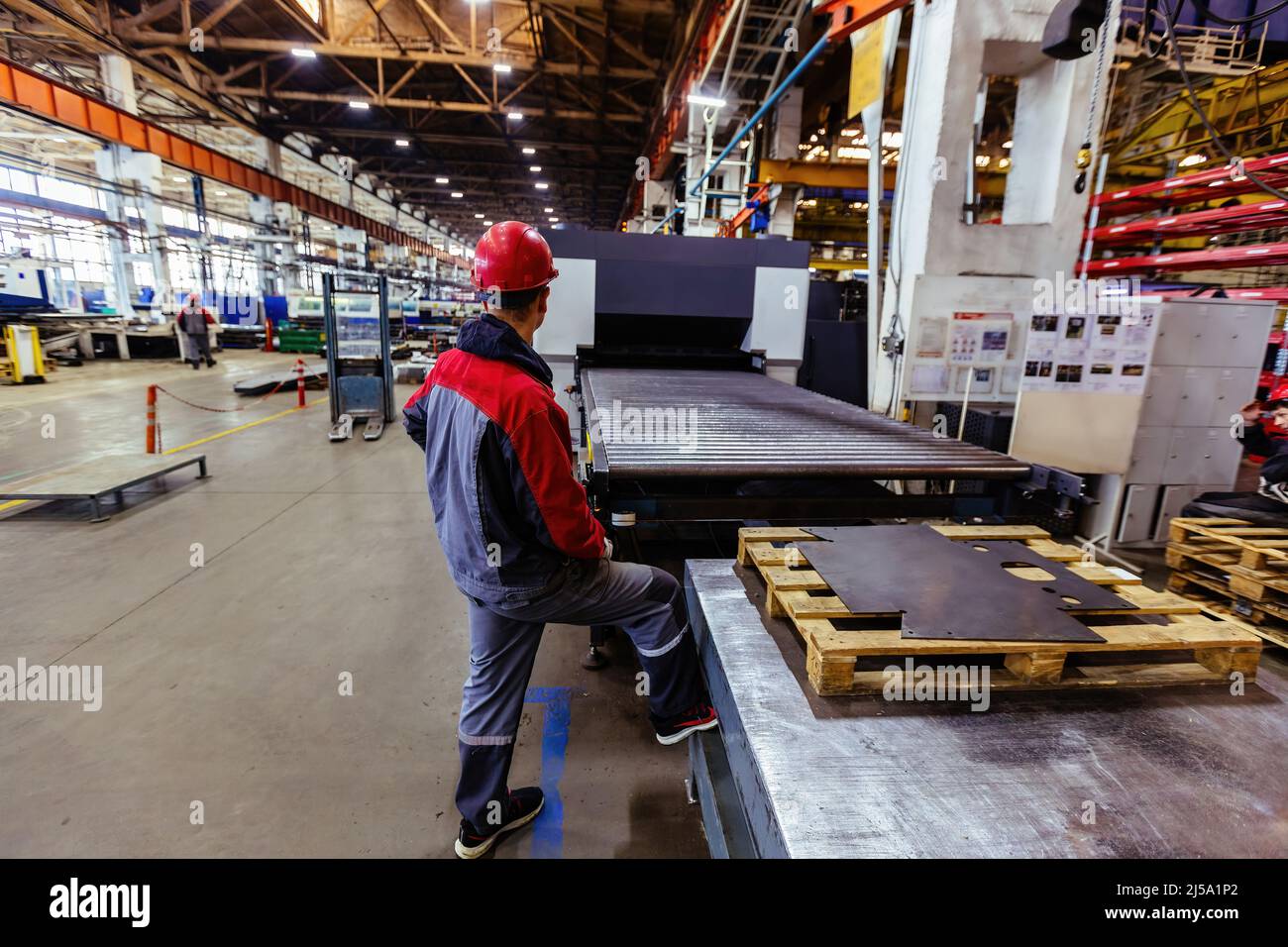Worker works with metal sheet forming machine at the metalwork factory ...