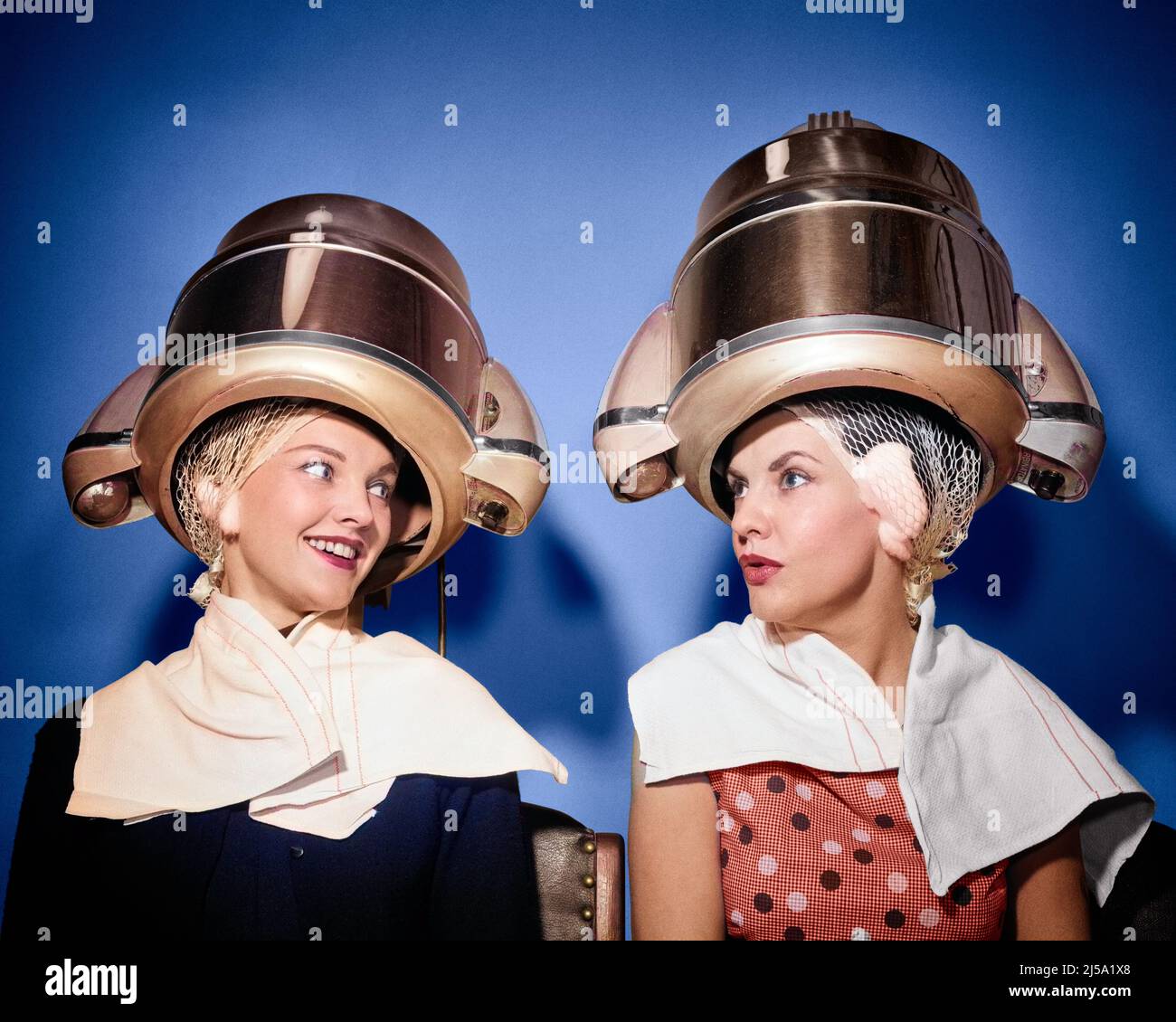 1950s TWO WOMEN SITTING UNDER BEAUTY SALON HAIR DRYERS WEARING HAIRNETS ...