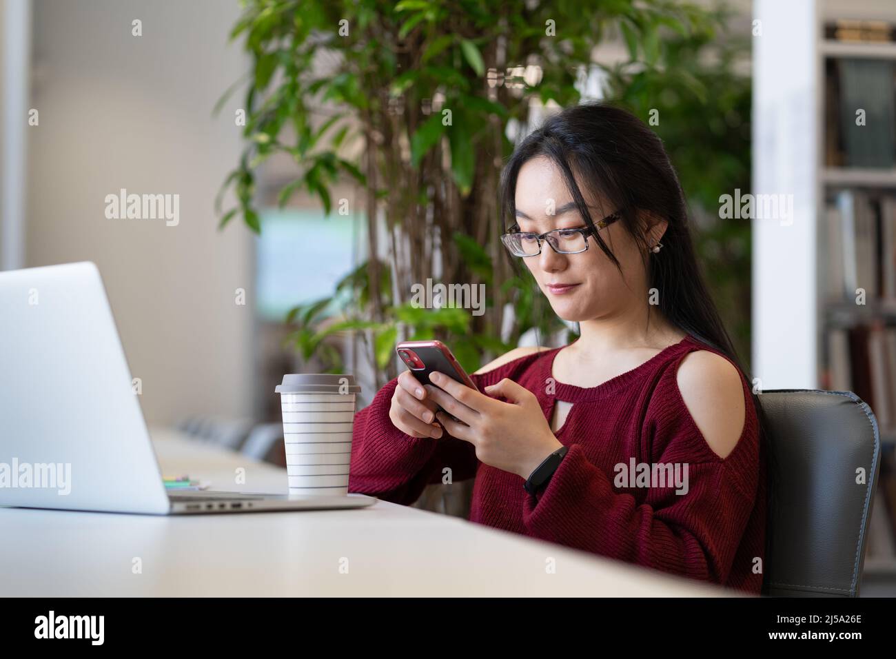 Happy asian student girl distracted from study using smartphone while ...