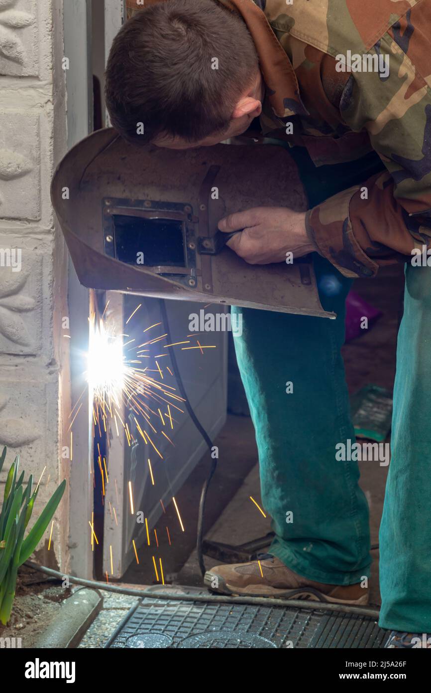 Electric welding. Electric welder welds metal parts Stock Photo - Alamy