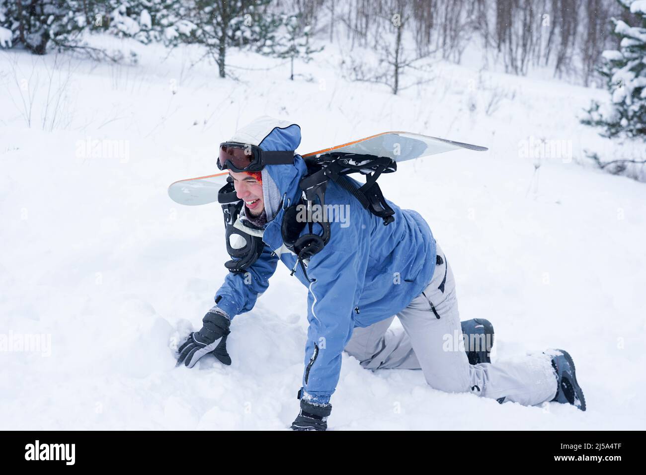 The guy snowboarder goes on a snowy slope. He is holding a snowboard ...