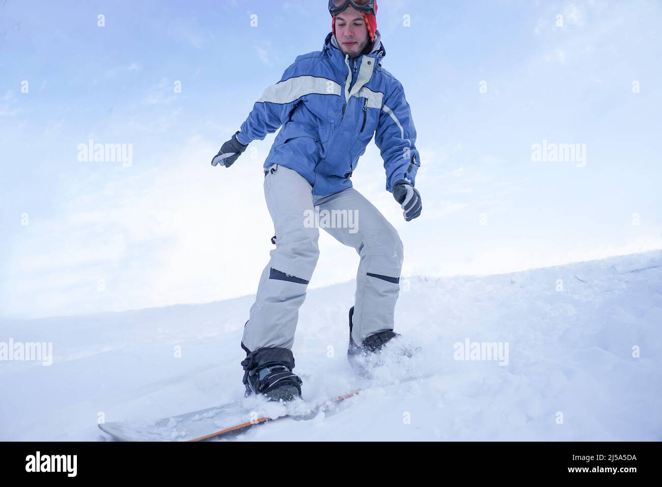 A snowboarder rides on a mountain slope with a snowboard in ski ...
