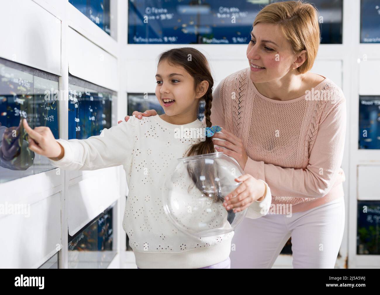 Cute girl with her mother customer buying tropical fish Stock Photo - Alamy