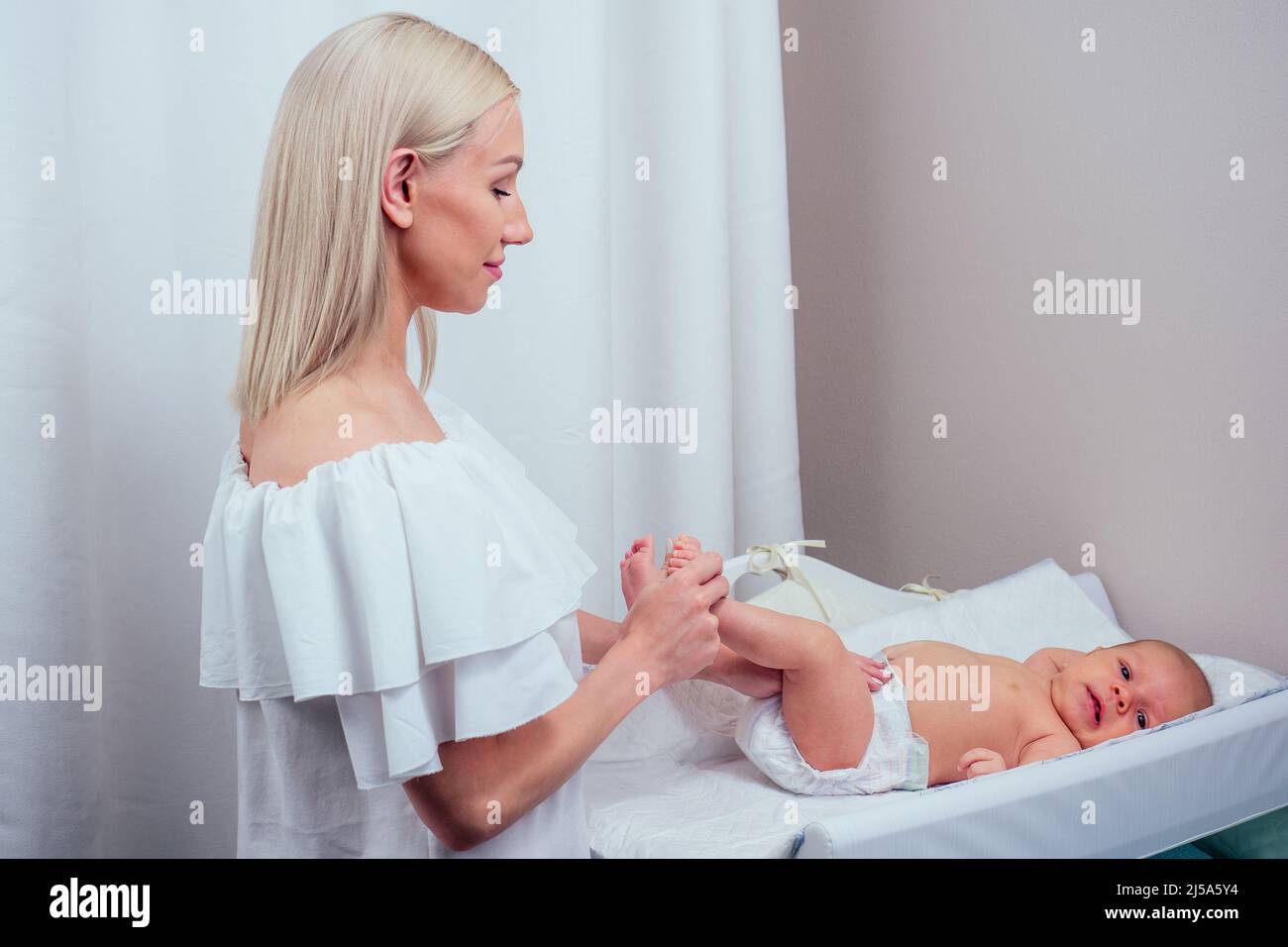 caucasian mother applying baby powder before putting diapers on her ...