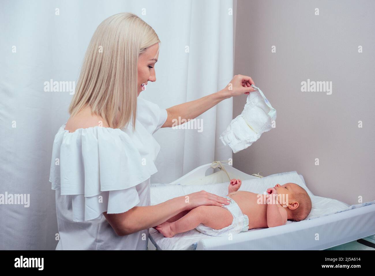 caucasian mother applying baby powder before putting diapers on her ...