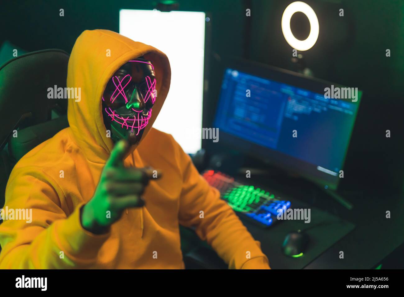 Cyber crimes concept. Professional hacker in yellow hoodie and scary ...