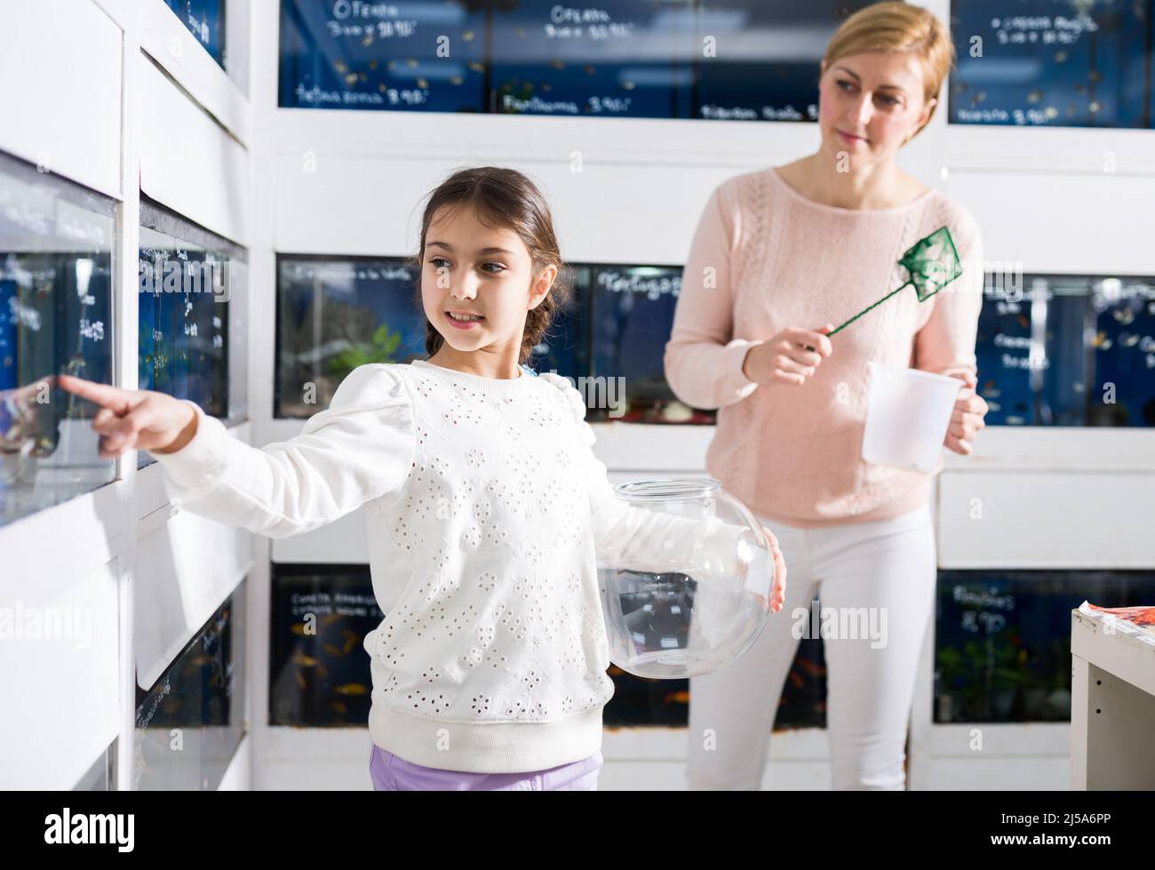 Girl with mother choosing aquarium fish Stock Photo - Alamy