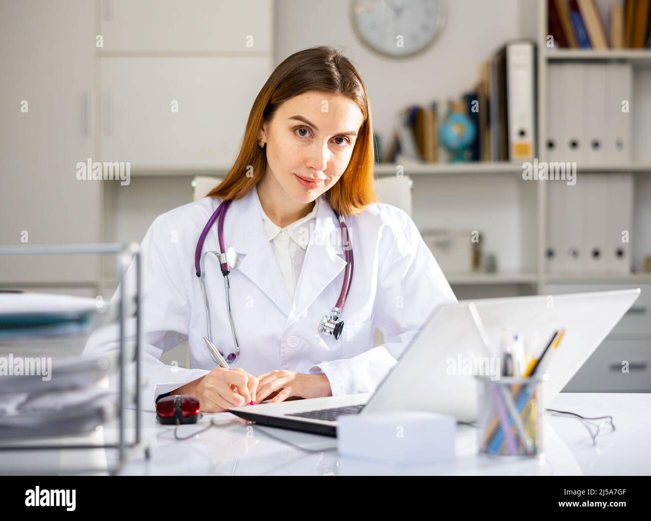 Focused woman doctor working in medical office using laptop Stock Photo ...